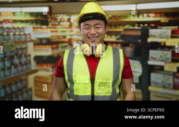 Young man with safety gear smiling in a supermarket setting with ...
