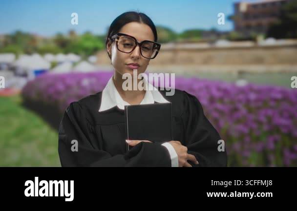 Hispanic woman judge in uniform standing confidently in a park with ...