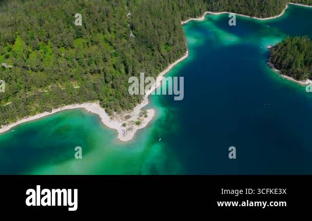 Aerial view of turquoise water lake with sandy shores and dense green ...