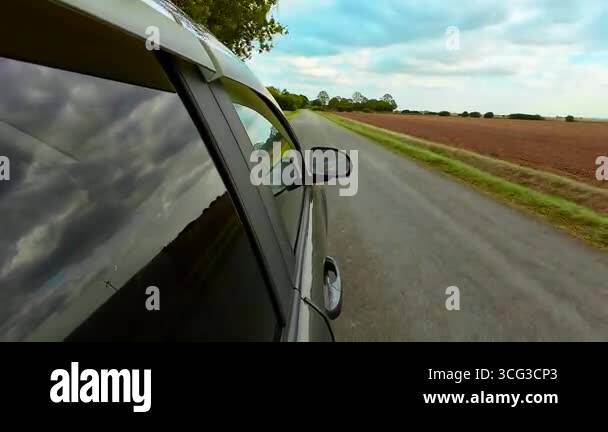 Vehicle driving along rural road in England countryside with left side ...