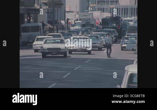 HOUSTON - 1972 - A traffic cop directs cars and pedestrians near a busy ...