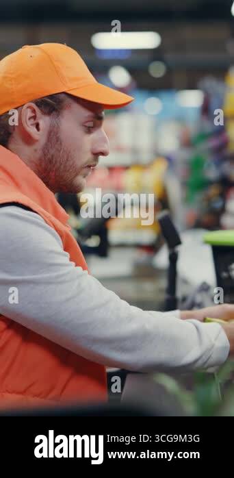 Portrait of handsome young man working at cash register in supermarket ...