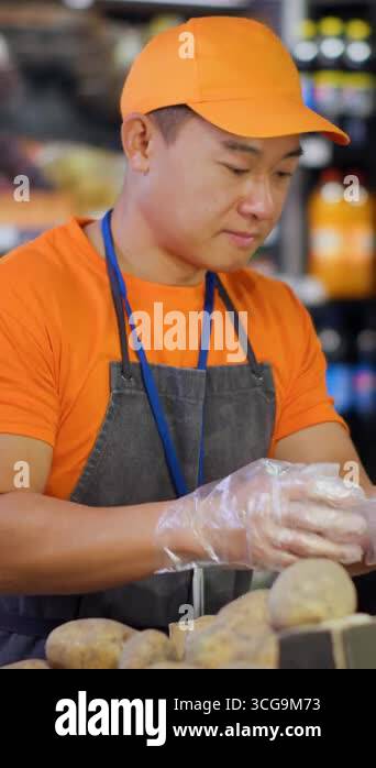 Portrait of positive chinese store assistant workman sorting vegetables ...