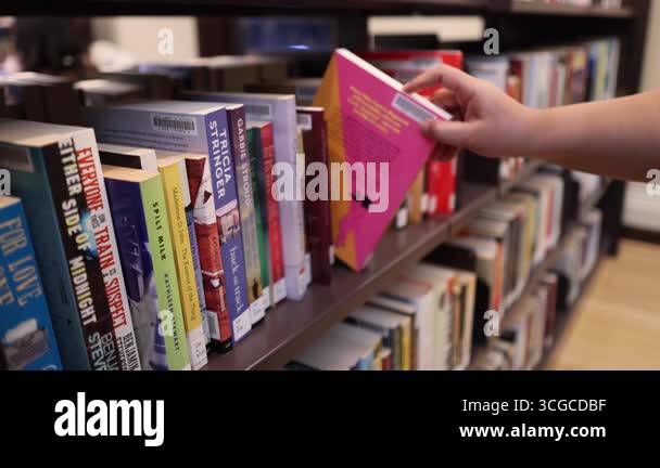 Person selecting a book from library shelf Stock Video Footage - Alamy