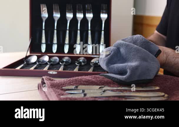 Man cleaning a silver knife with cloth, polishing cutlery set at home ...