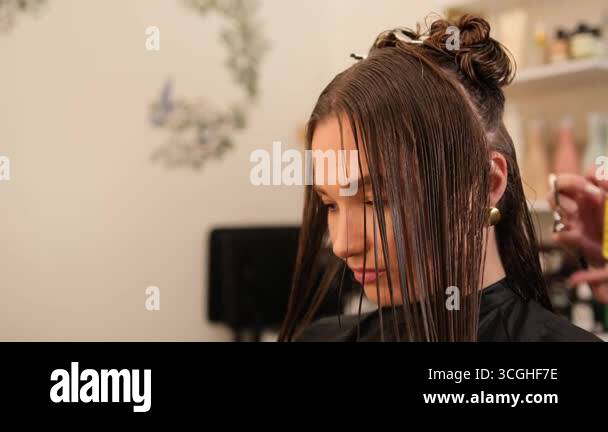 A client with sectioned hair sits ready for styling during a ...