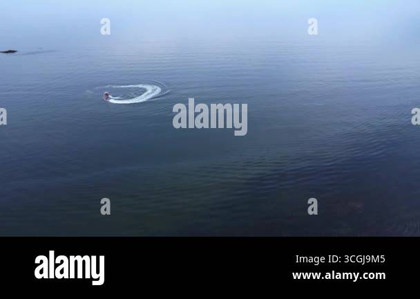 Aerial view of a small red and white fishing boat turning around on a ...