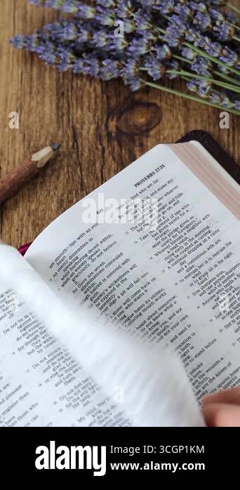 Studying and reading from open holy bible book on wooden table ...