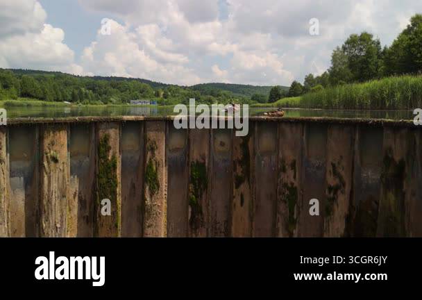 Aerial shot of a dam with a wooden spillway and a surrounding reservoir ...