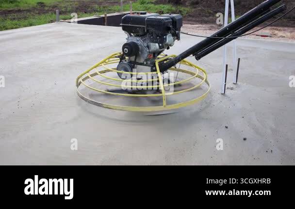Close-up of a construction worker operating a power trowel machine to ...