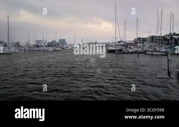 This low-flying drone footage glides over a calm winter harbor lined ...