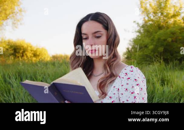 A young woman is happily enjoying the experience of reading a ...