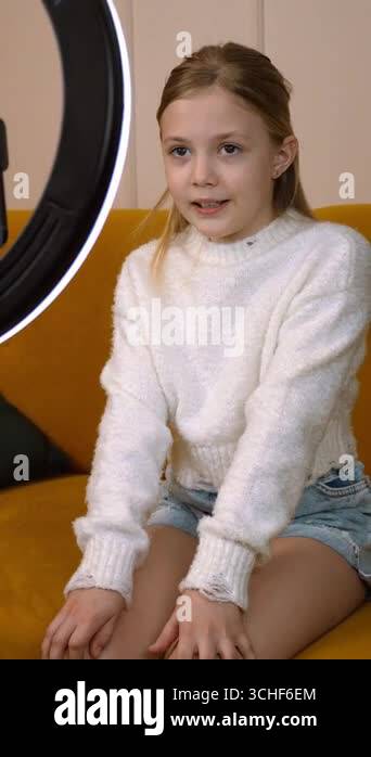 Young female creator recording video content using smartphone and ring ...