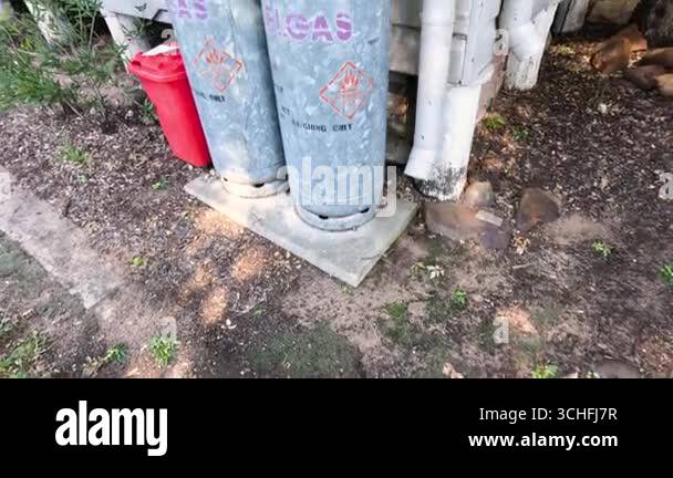 Gas cylinders beside a house with red bin Stock Video Footage - Alamy
