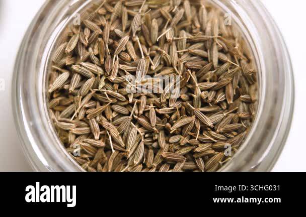 Dry cumin seeds falling into glass jar. Organic Asian aromatic spice ...