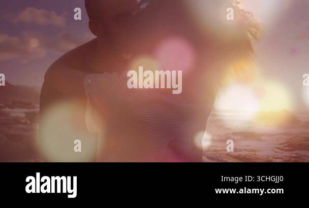 Lens-flare overlay fading, couple embracing and kissing on rocky sunset ...