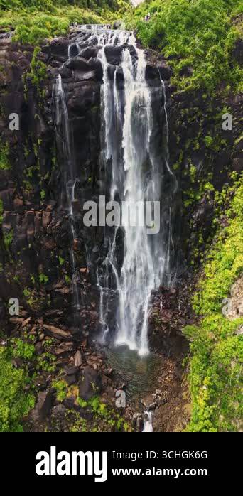 A breathtaking waterfall cascades down rugged cliffs surrounded by ...