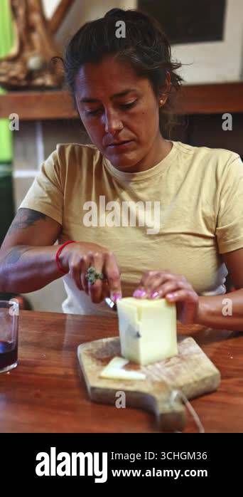 A woman in the Basque Country slices cheese on a wooden cutting board ...