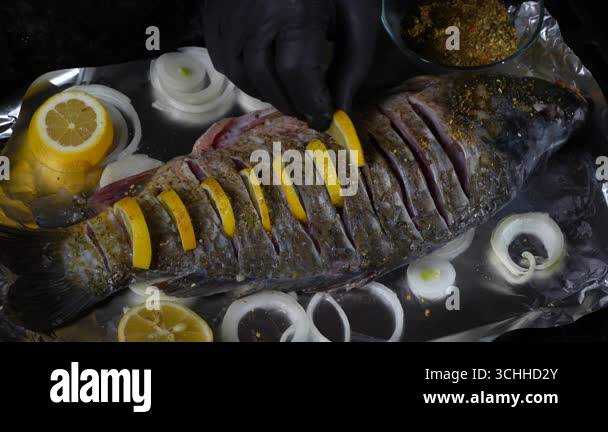 The cook prepares carp fish with lemon on baking tray for baking in the ...