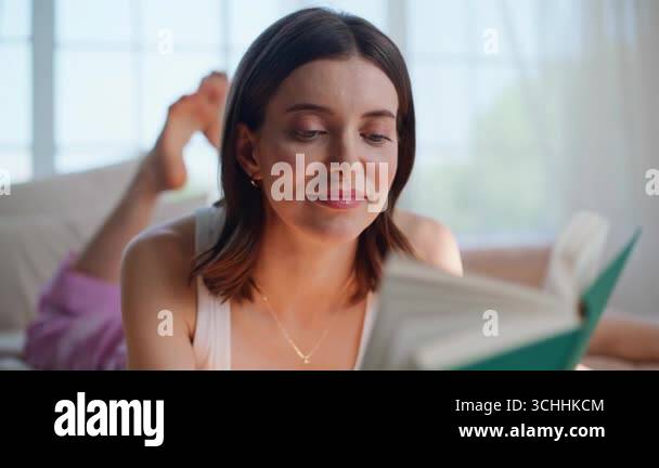 Calm brunette reading novel relaxing at soft bedding closeup. Smiling ...