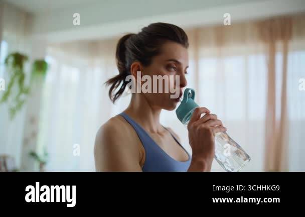 Athletic lady drinking clean water feeling thirsty after morning home ...