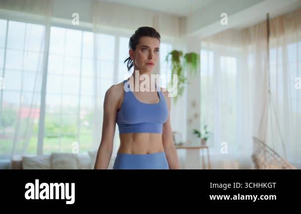Woman flexing muscles with dumbbells standing light living room closeup. Strong sportswoman ...