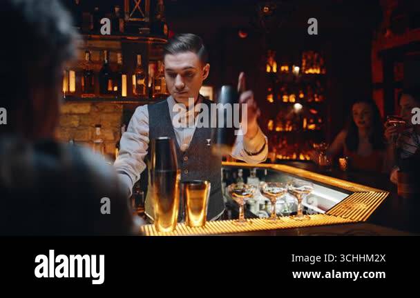 Skilled bartender using shaker working at luxury restaurant at night ...
