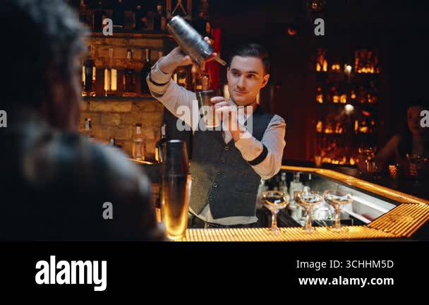 Experienced barman pouring alcohol beverage in shaker at modern ...