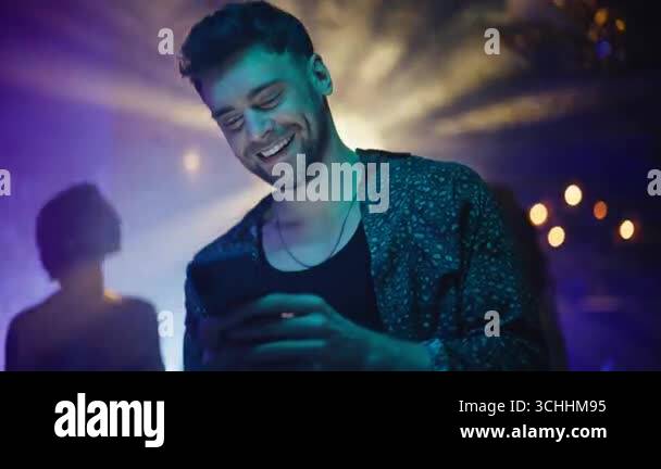 Clubbing man reading smartphone message at bright dancefloor closeup ...