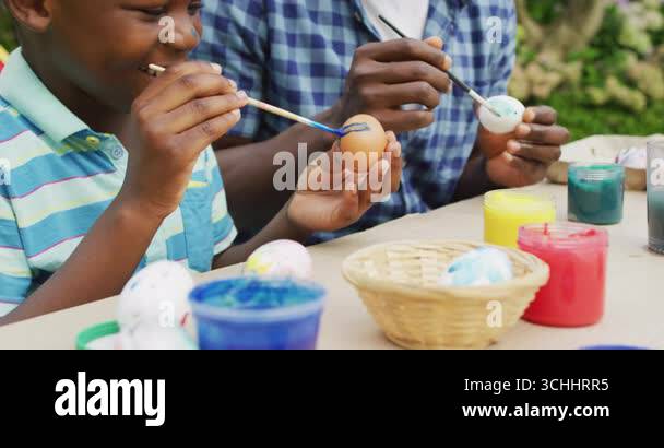 Animation of happy african american father and son painting easter eggs ...