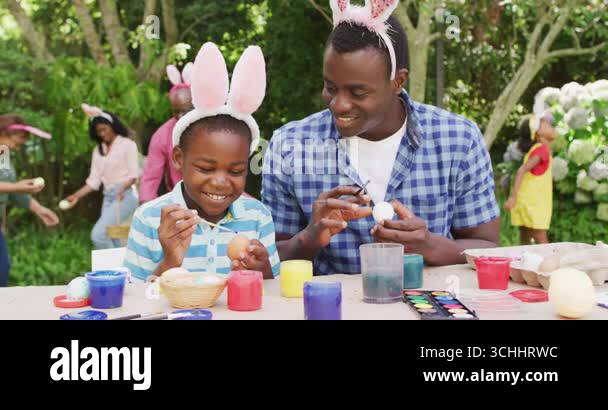 Animation of happy african american father and son painting easter eggs ...