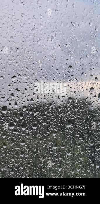 Raindrops on glass with blurred view outside create calm, melancholy ...