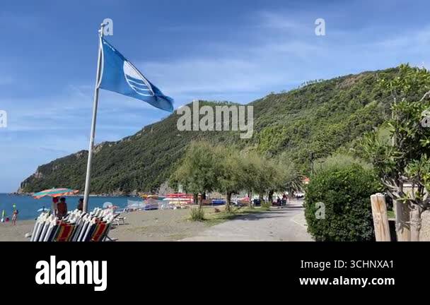 Blue flag on beach by sea. Nature and ecology, sky. Mountains and ...