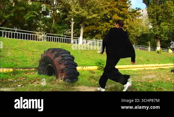 A guy does an acrobatic somersault in parkour style on a huge tractor ...