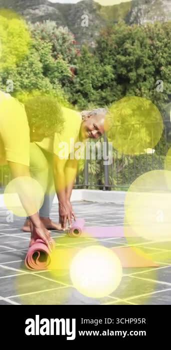 People rolling yoga mats on outdoor terrace with glowing yellow circles ...