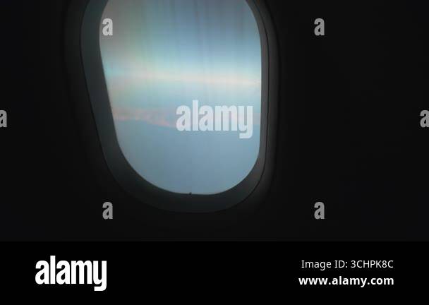 Inside airplane, view through window reveals changing landscape with ...