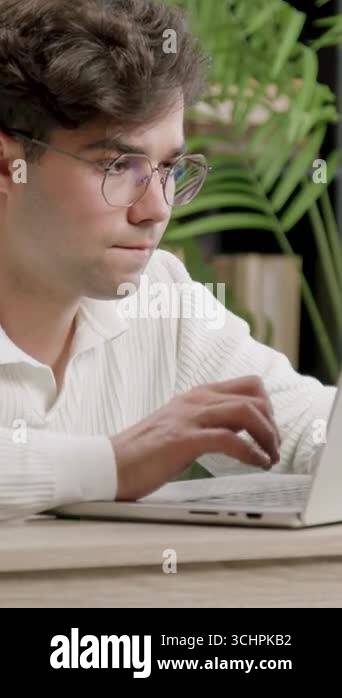 Man types report on laptop with focused expression and steady hands ...
