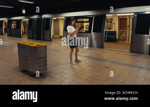 Female traveler interacts with smartphone at subway station, focused on ...