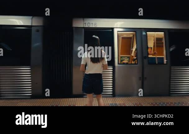 Female commuter waits at subway station as train doors open, ready to ...