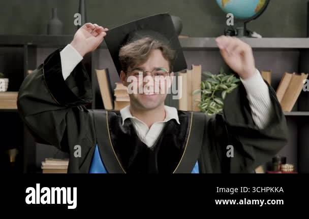 Portrait of a fresh graduate boy with cap, gown and black scarf smiling ...