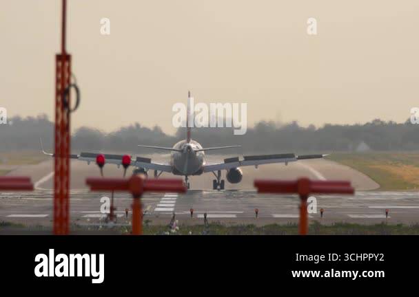 Rear view, jet passenger plane slowing down after landing, spoilers up ...