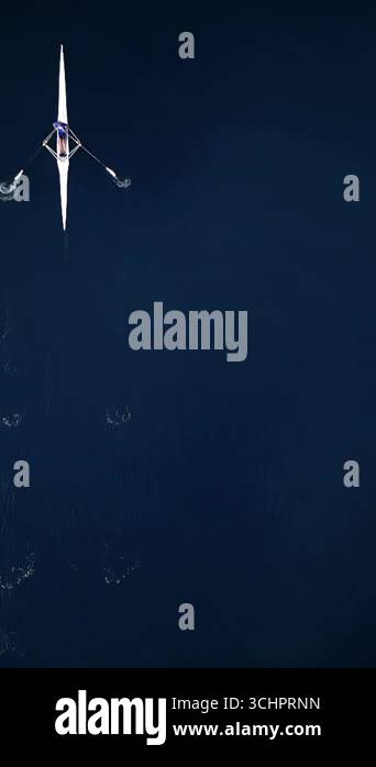 Drone aerial video of a single rowing athlete moving across calm deep ...