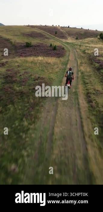 Vertical aerial video of a motorcyclist riding a dirt bike on a ...