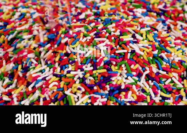 A dense pile of rainbow sprinkles is shown from a low side angle ...