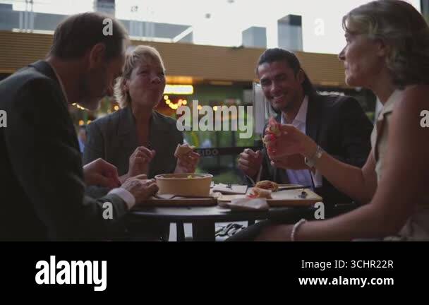 Professional team enjoying relaxed lunch break outdoors, sharing ...