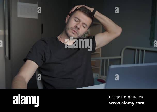 Man sitting at desk with laptop stretching neck by tilting head with ...