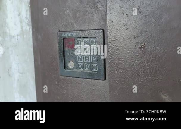 A persons hand holds a magnetic key fob to an electronic intercom panel ...