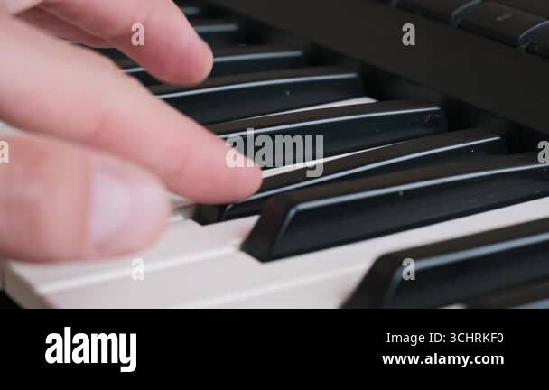A musicians hand moves across a keyboard, playing a melody on both the ...