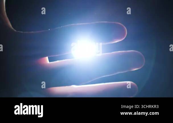 Close-up of a human hand moving over a bright flashlight beam in the ...