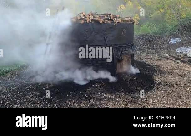 Process of traditional charcoal production in big stoves, burning under ...